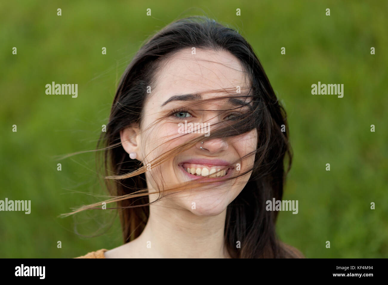 Outdoor portrait of beautiful happy girl laughing while the wind moves ...