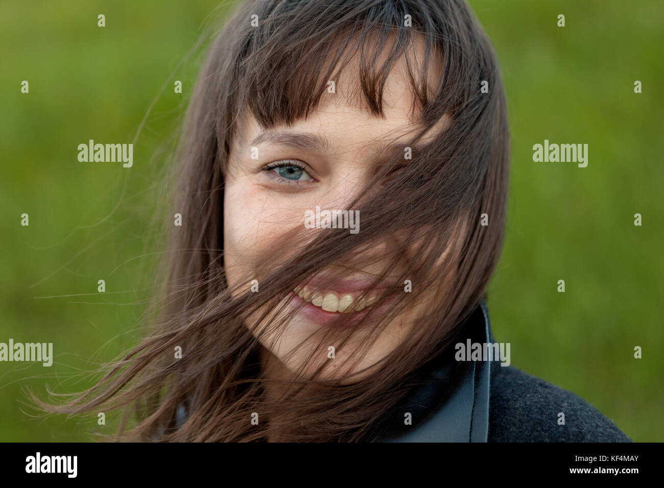 Outdoor portrait of beautiful happy girl laughing while the wind moves ...