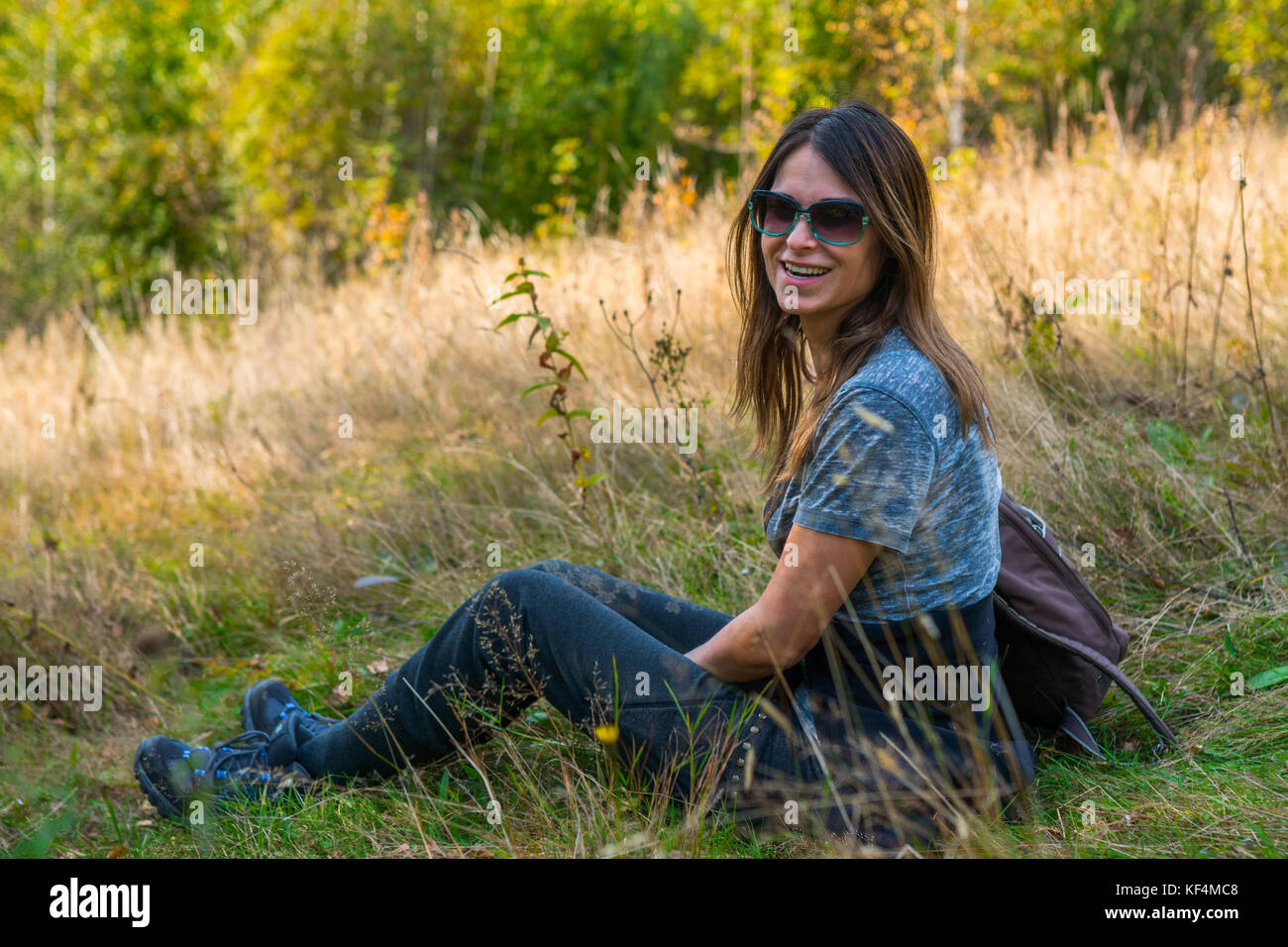 Woman hiker resting in grass by the forest Stock Photo - Alamy