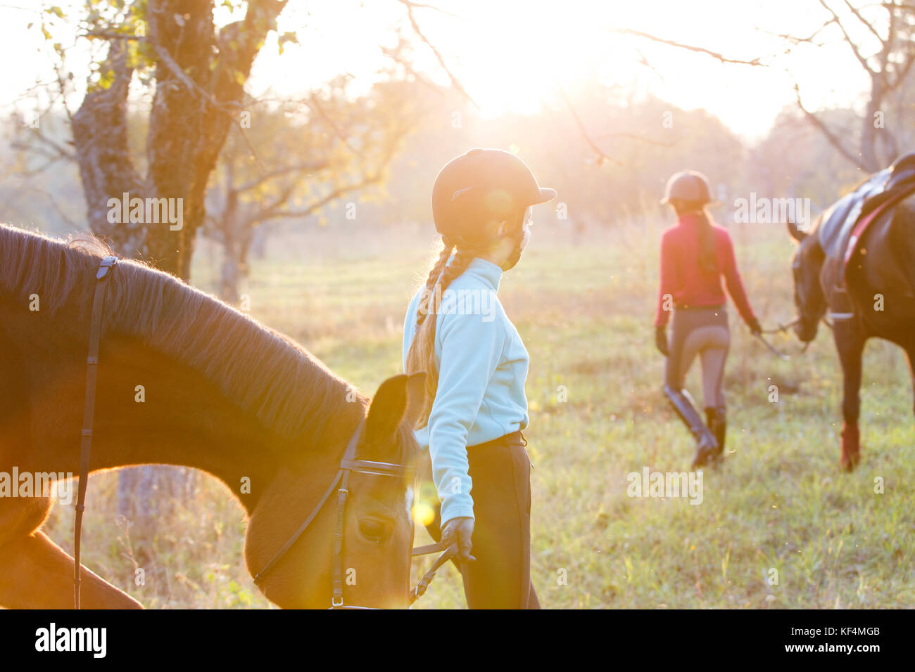 Group of rider girls walking with horses in park. Equestrian recreation ...