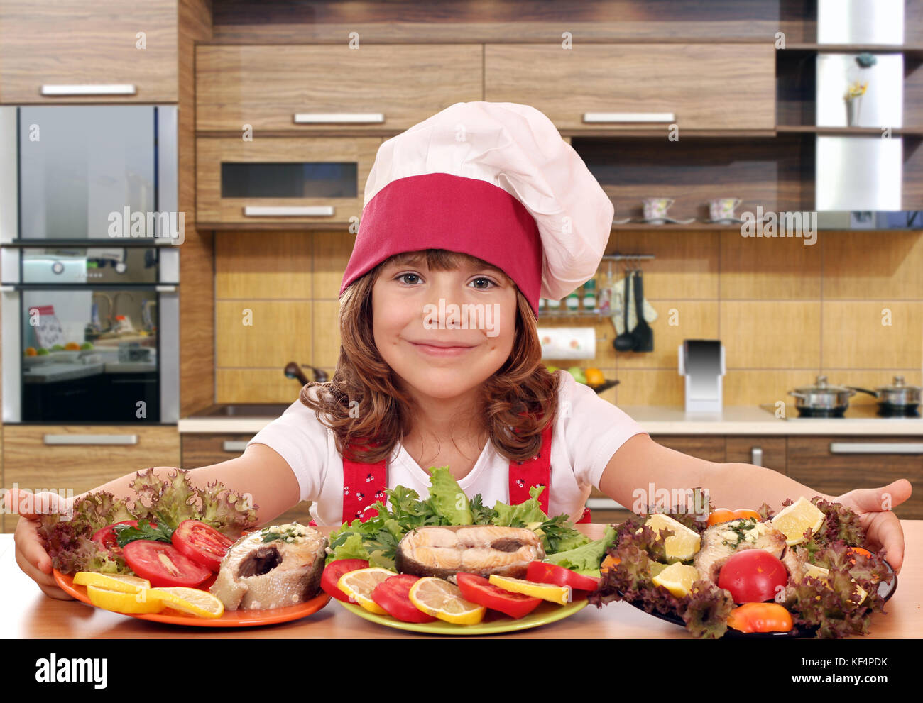 beautiful little girl cook with prepared salmon seafood in kitchen ...