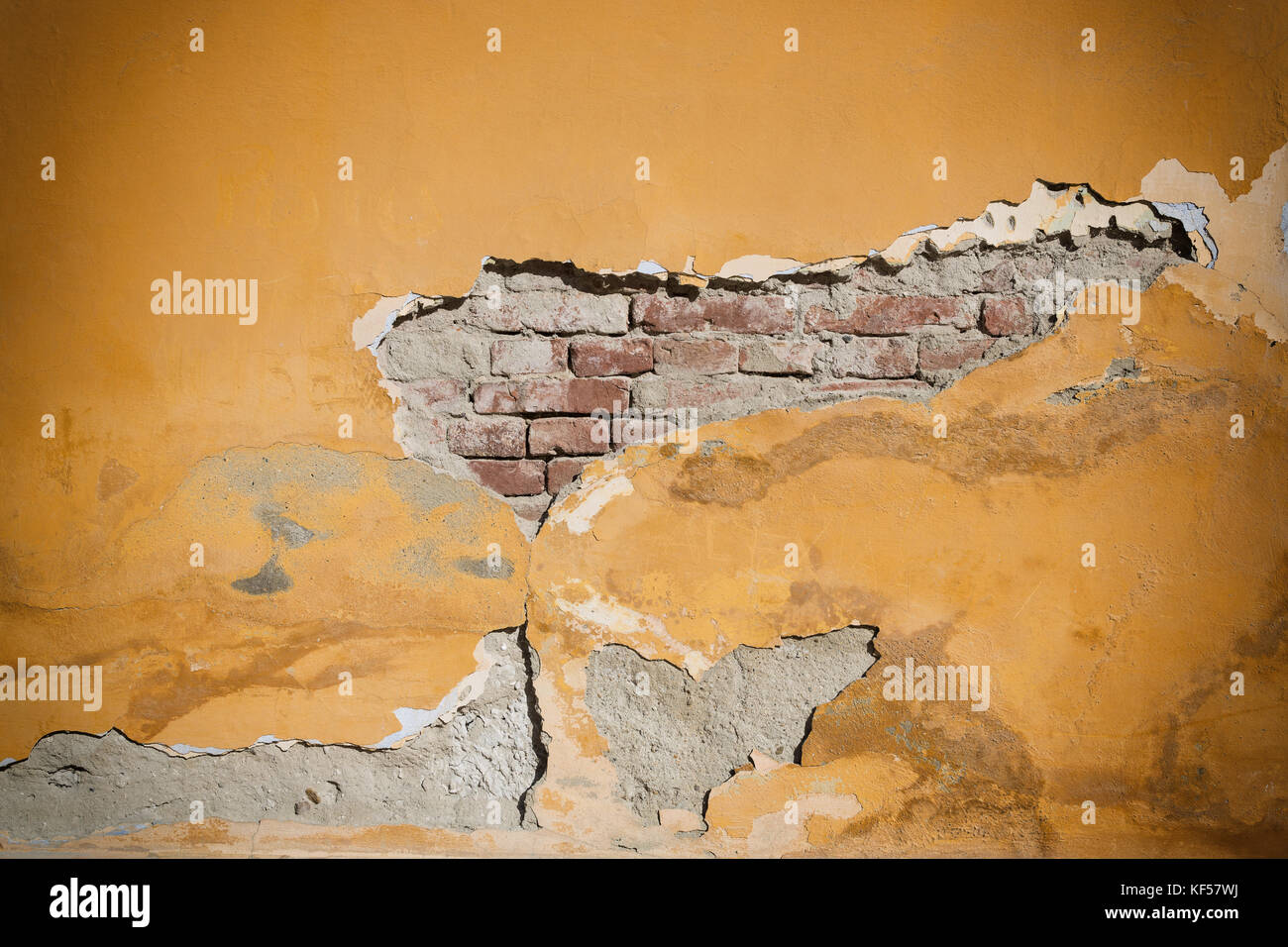 Damaged brickwall with a hole. Damaged plaster on brickwall. Old brick ...