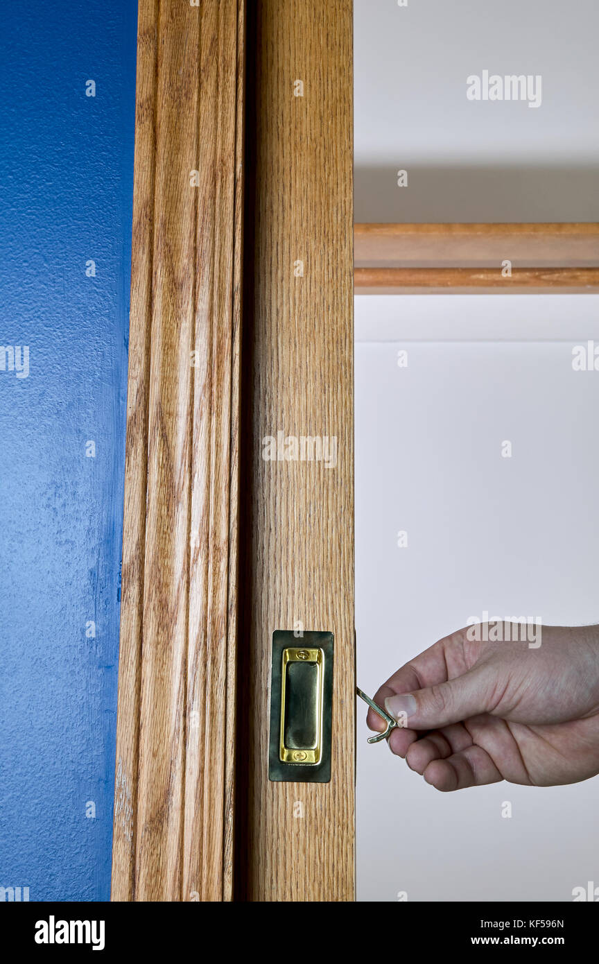 Someone unlocking an open small wooden and metal pocket door using ...