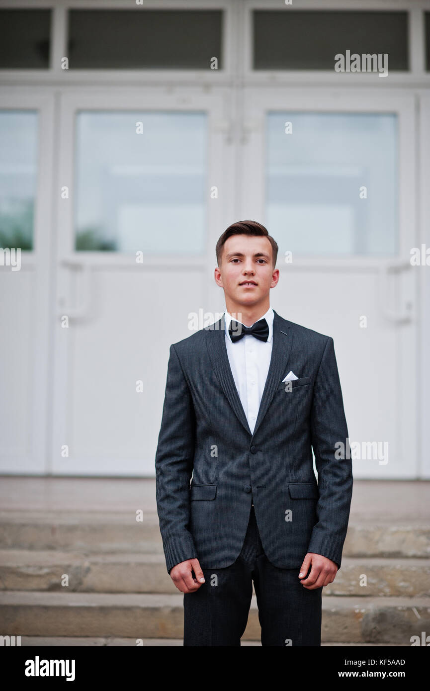 Portrait of a handsome high school graduate in stylish tuxedo posing on ...