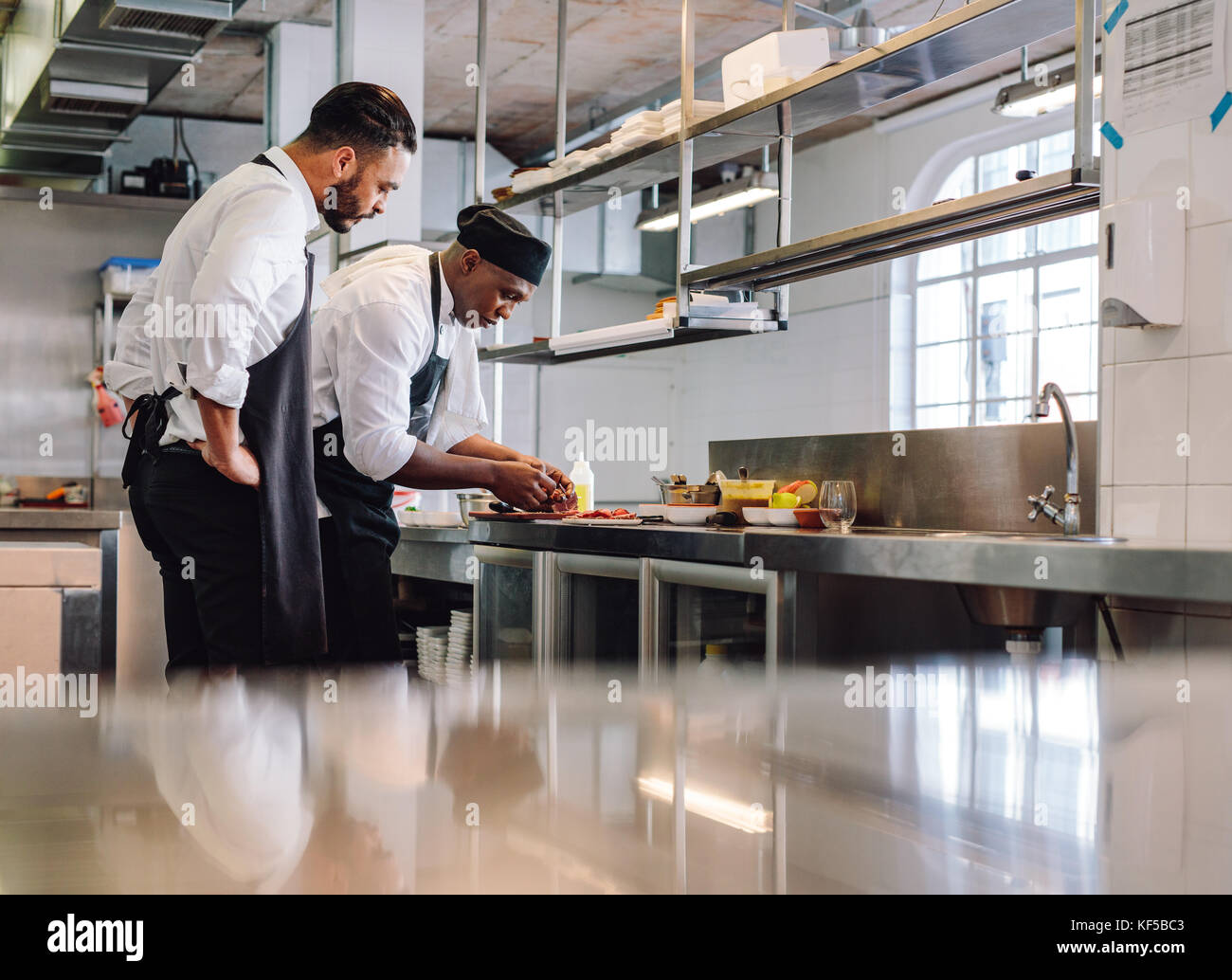 Two male cooks preparing food on restaurant kitchen counter. Chefs ...