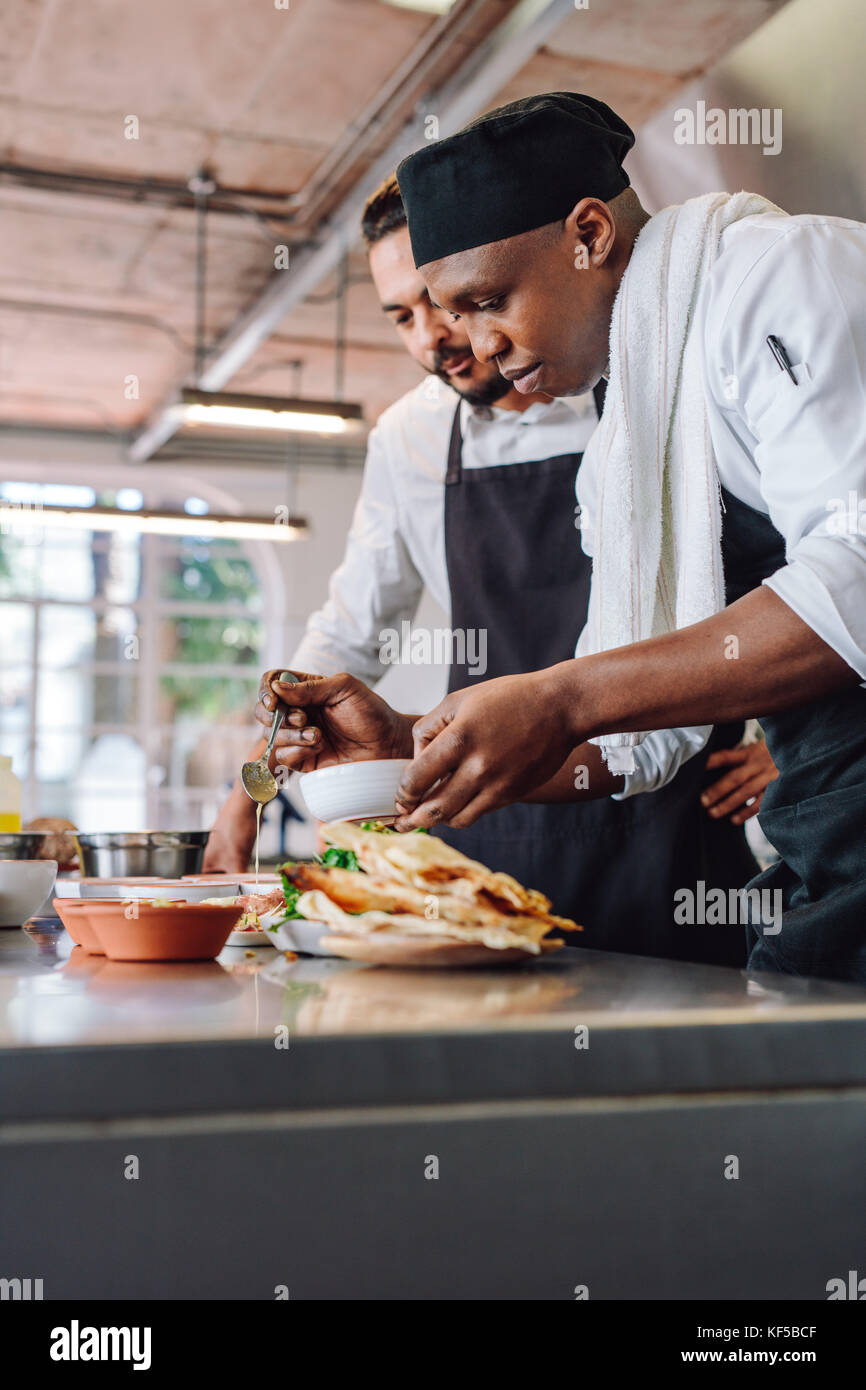 Two professional cooks working at restaurant kitchen together. Chefs ...