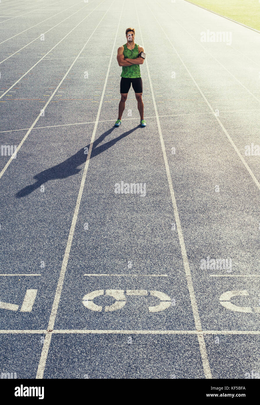 Runner standing on running track with hands folded. Athlete wearing ...