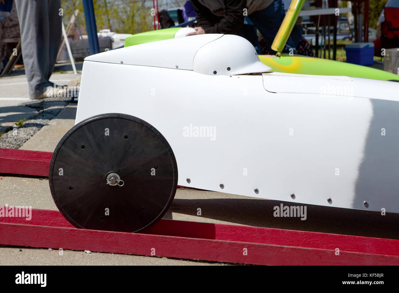 White soap box derby racer and helmet on red metal tracks on a ramp ...