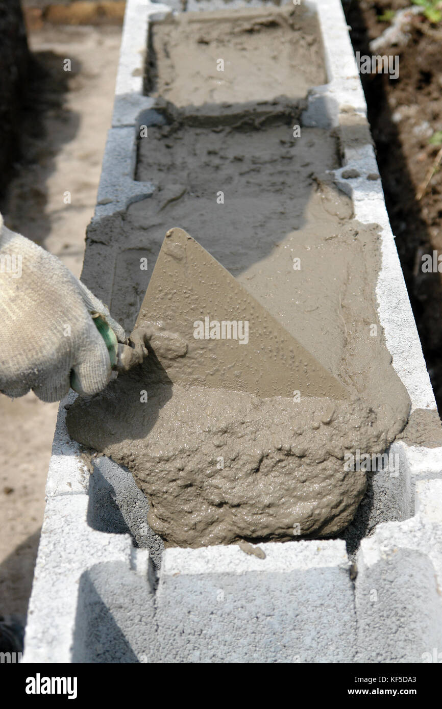Closeup of mason hand spreading mortar with trowel in concrete ...