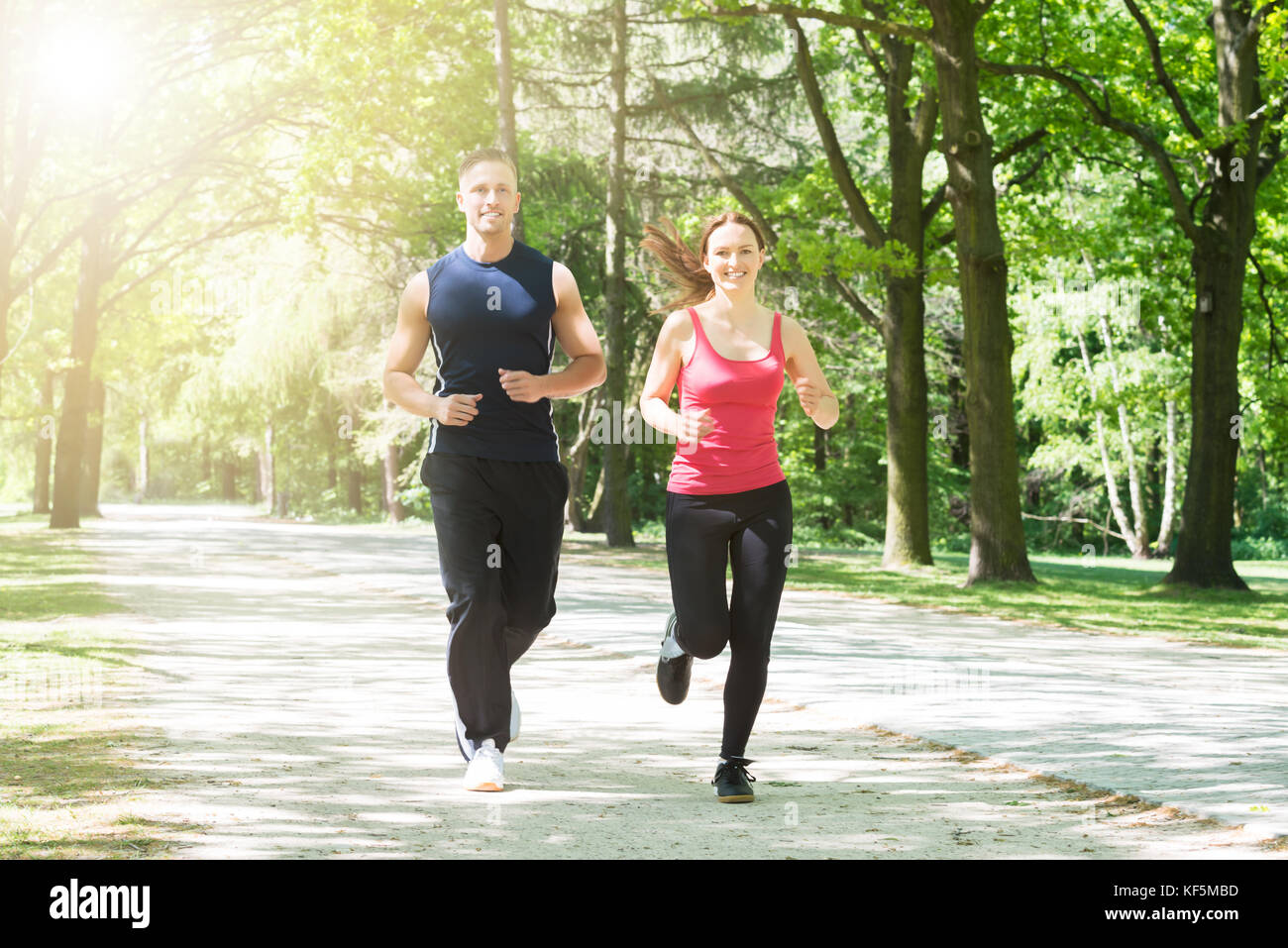 Photo Of Young Happy Couple Jogging In Park Stock Photo - Alamy
