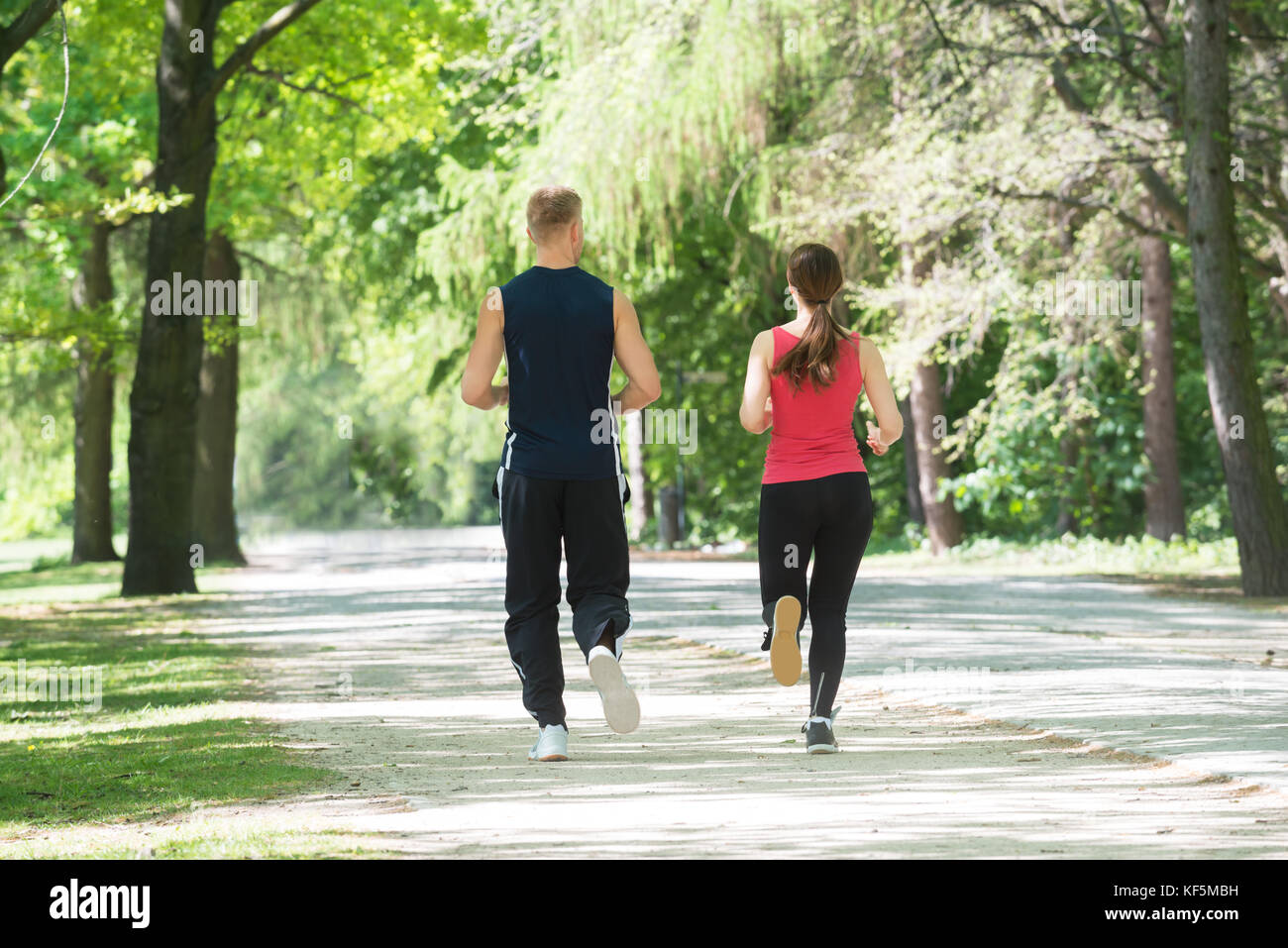 Rear View Of Young Athletic Couple Jogging In Park Stock Photo - Alamy