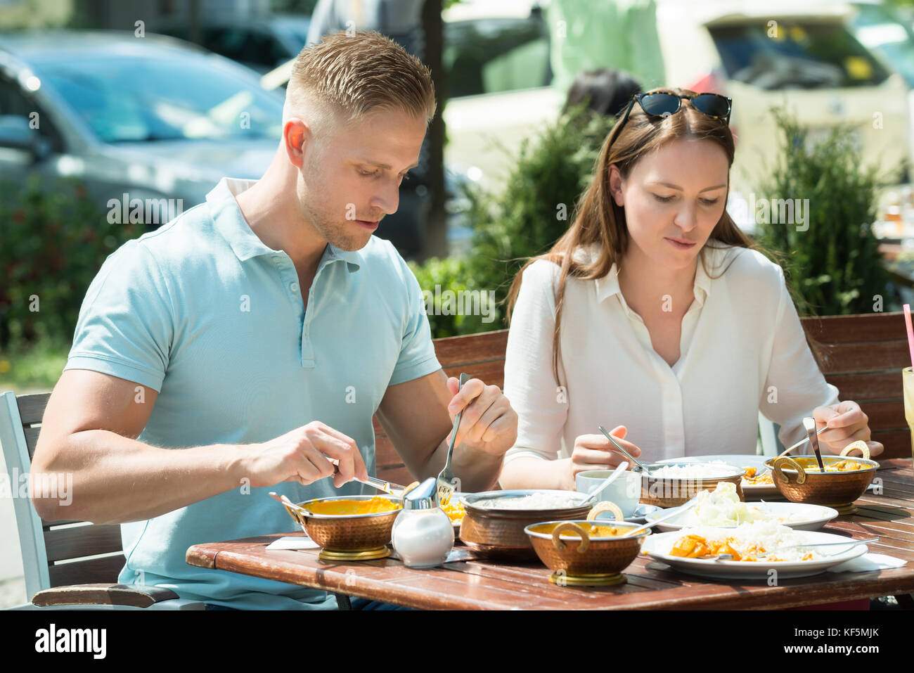 Young Couple Sitting On Bench Having Lunch Together Stock Photo - Alamy