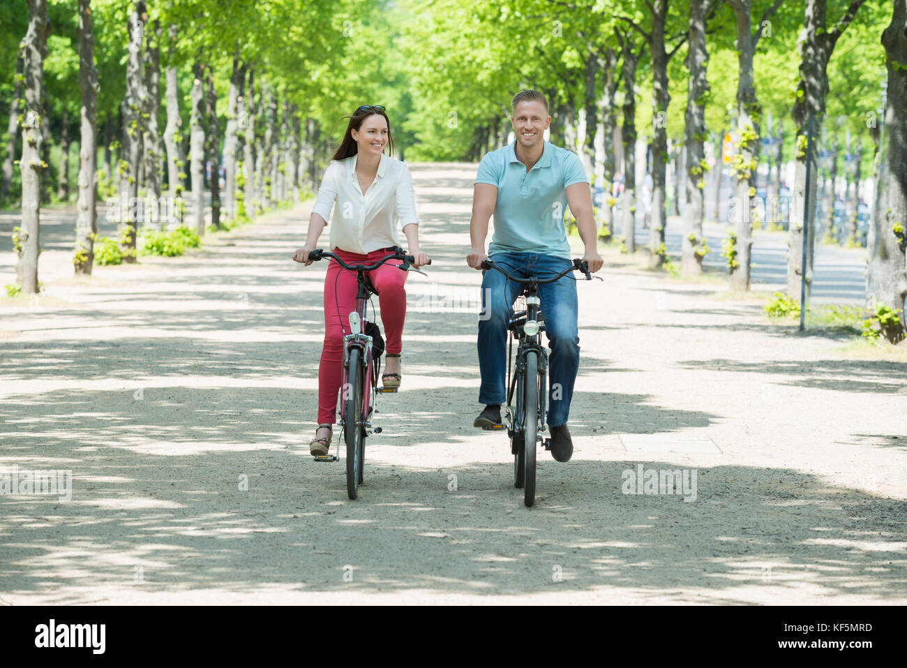 Young Happy Couple Riding Bicycle In Park Stock Photo - Alamy