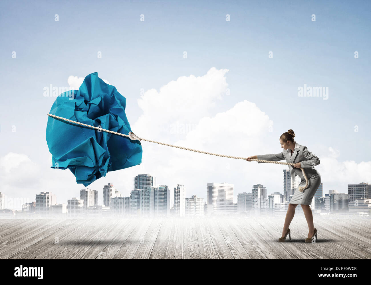 Woman pulling with effort big crumpled ball of paper as creativity sign ...
