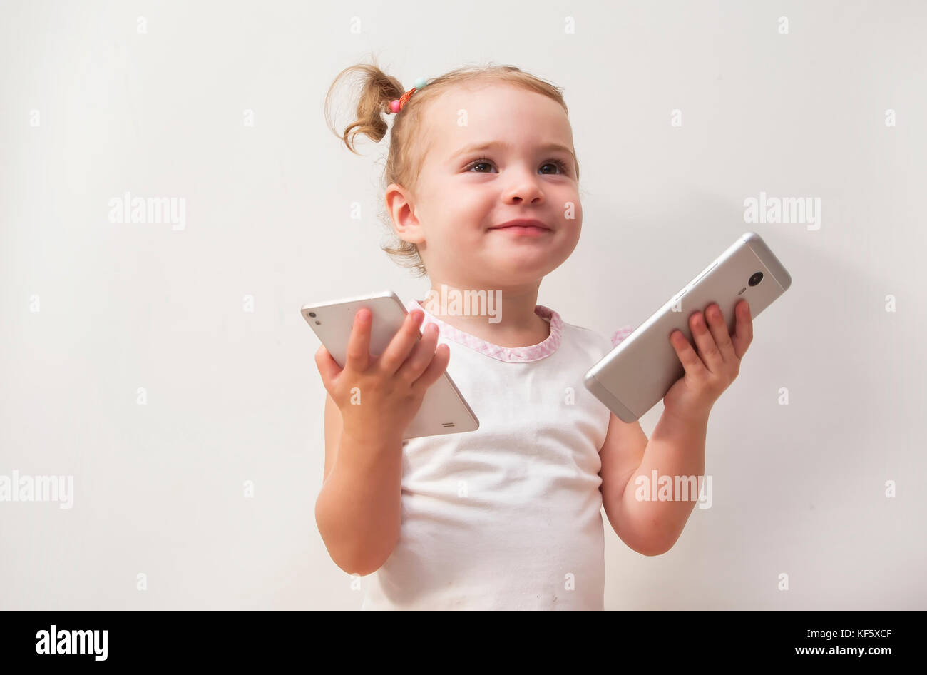 cute baby girl playing with two mobile phones on white Stock Photo - Alamy