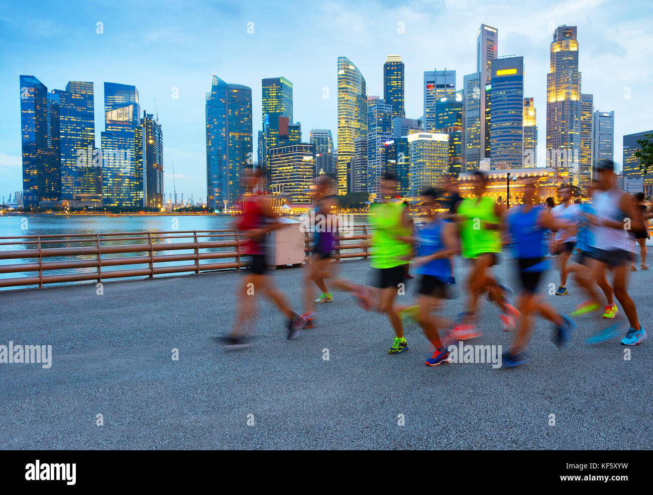 Group of runners on Singapore quayside at twilight, Singapore Downtown ...