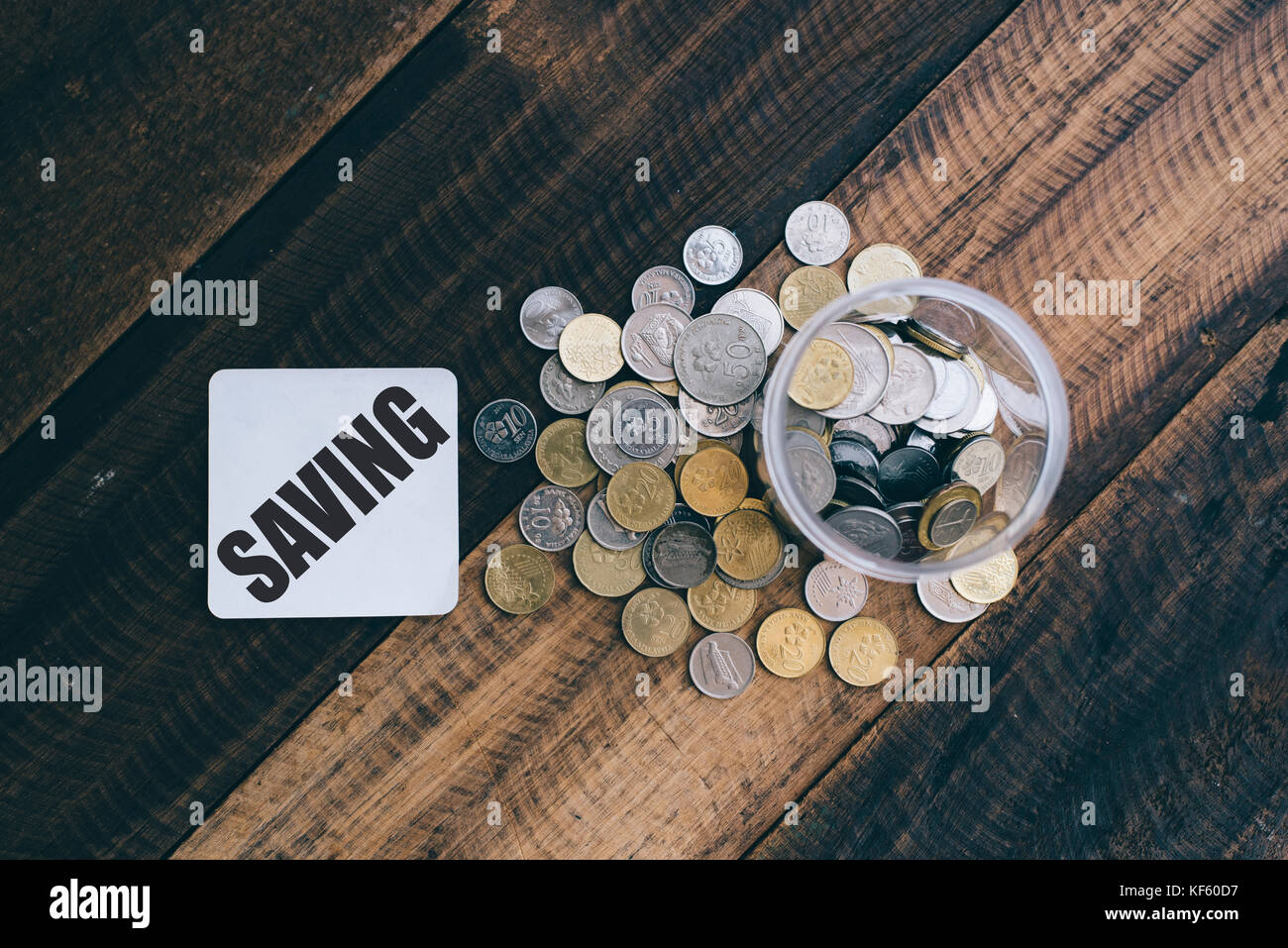 saving concept - coins in a jar with " saving " note on a wooden table ...
