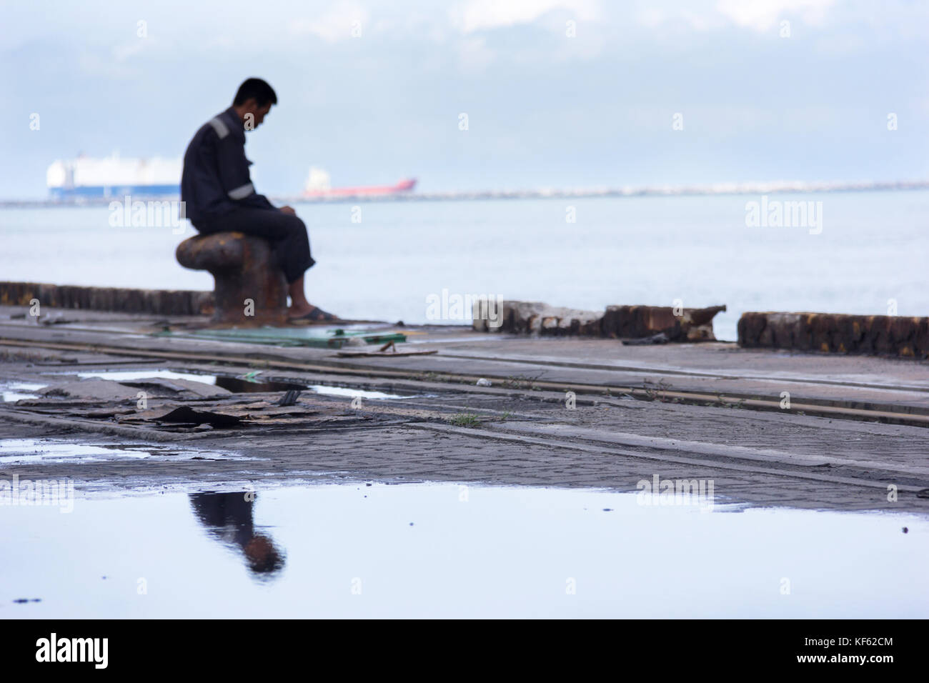 tired dock worker labor sitting on the pole after finishing work with ...