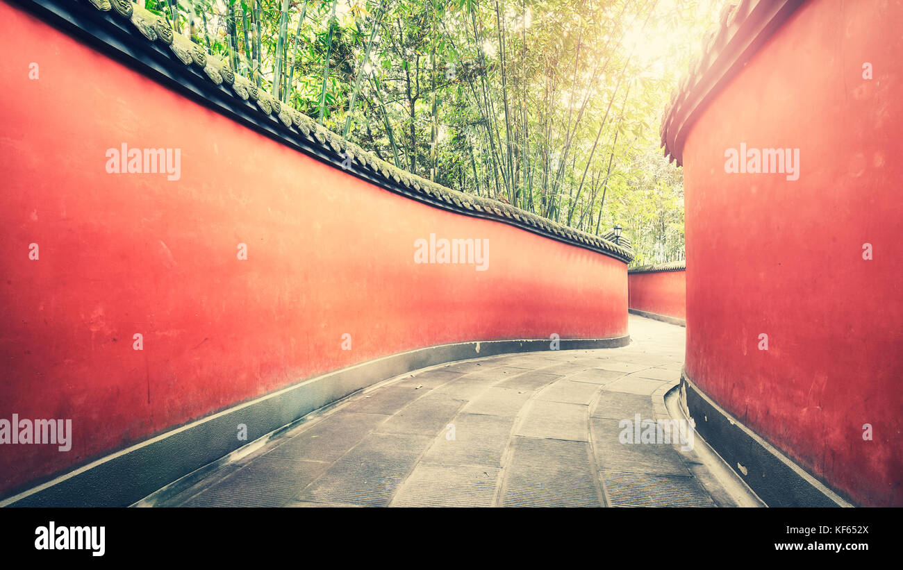 Curvy red walls passage surrounded by bamboo forest, color toning ...