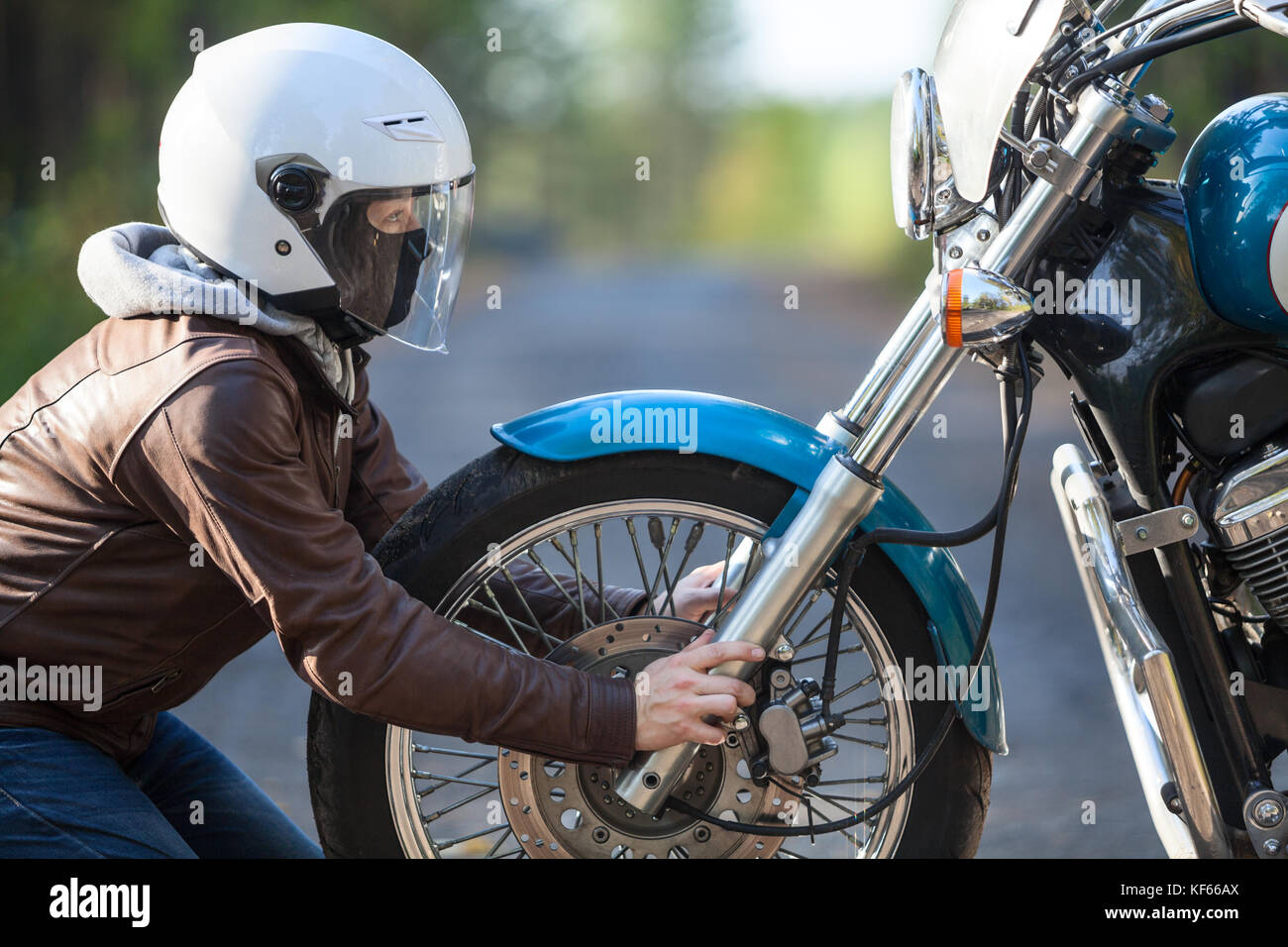 Female rider sitting on the kneels on the ground against motorbike ...