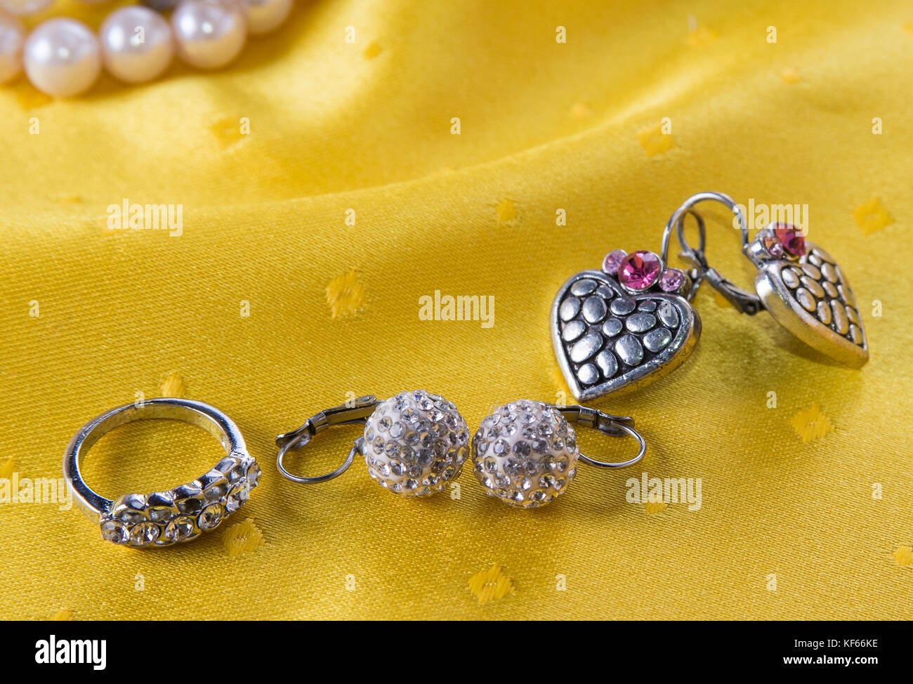 Two pairs of earings and ring on the yellow background Stock Photo - Alamy