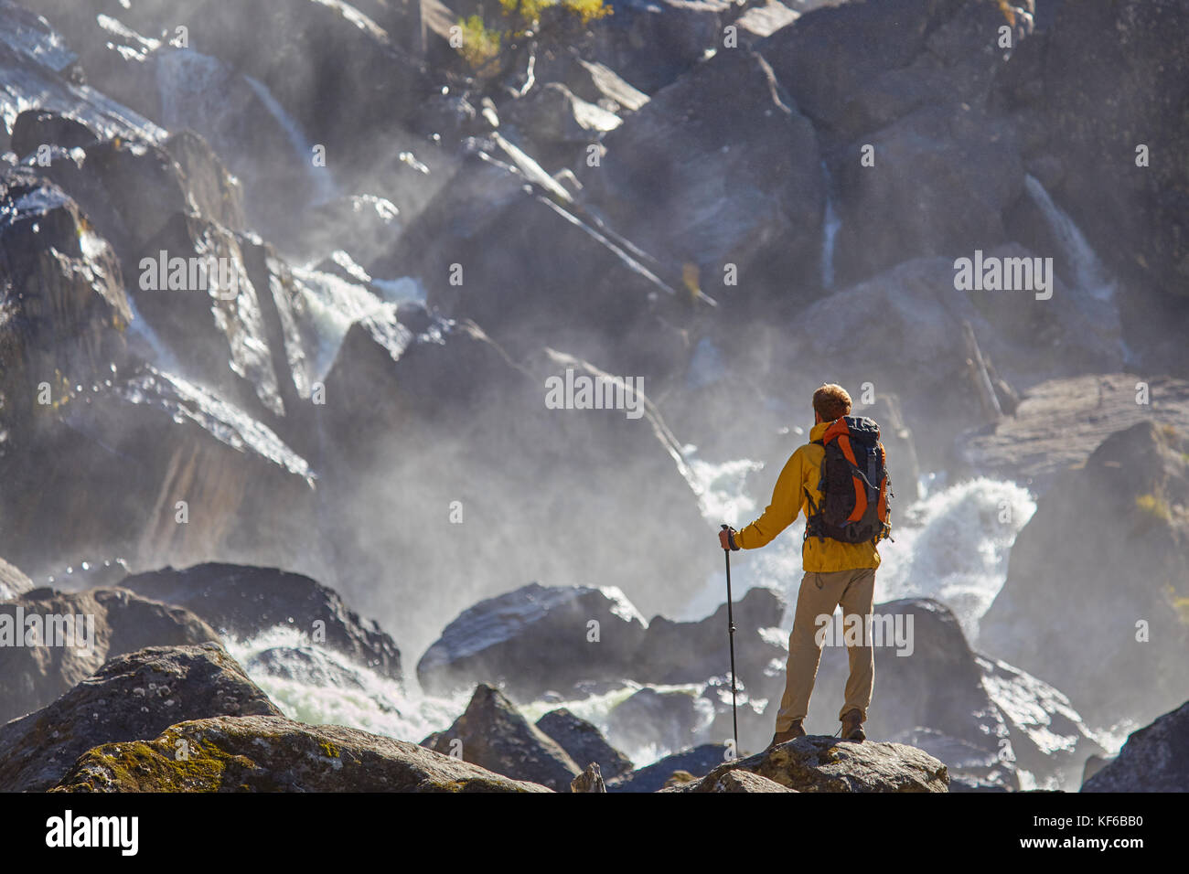 Hiker hiking with backpack looking at waterfall Stock Photo - Alamy