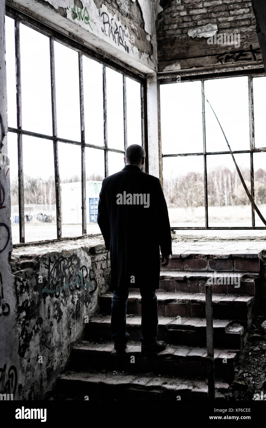 Rear view of a mysterious male figure standing on the steps inside a ...