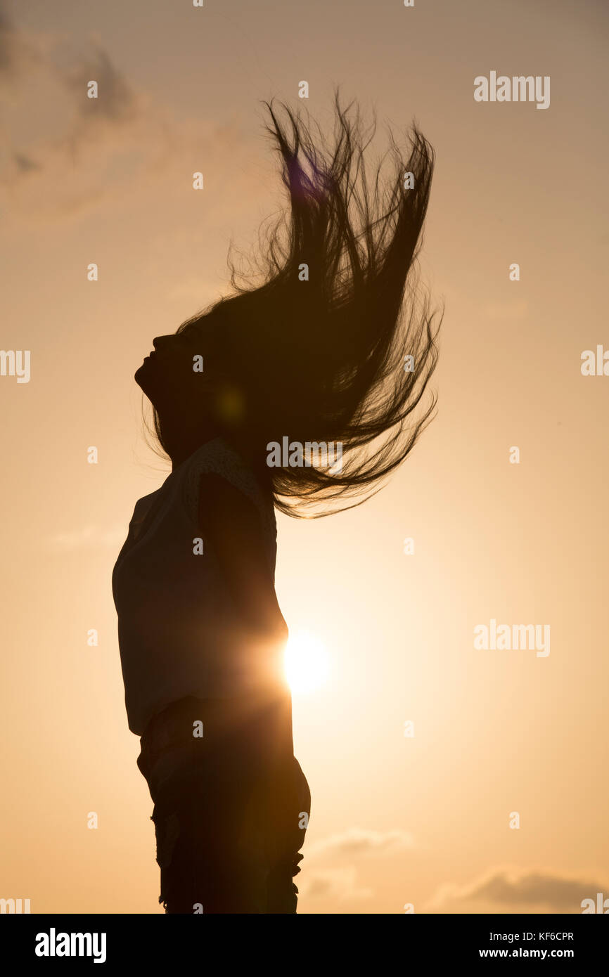 Silhouette of a young woman flicking her hair at sunset Stock Photo - Alamy