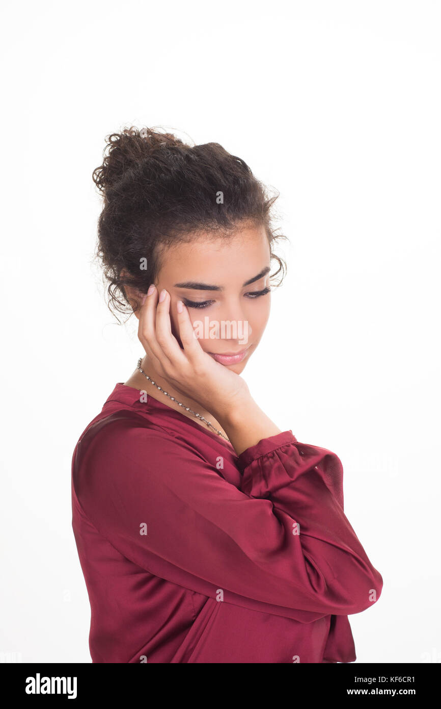 Beautiful young woman looking down thinking hand touching face aginst a ...