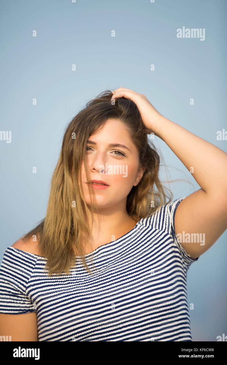Young woman hand on head looking away outdoors Stock Photo - Alamy