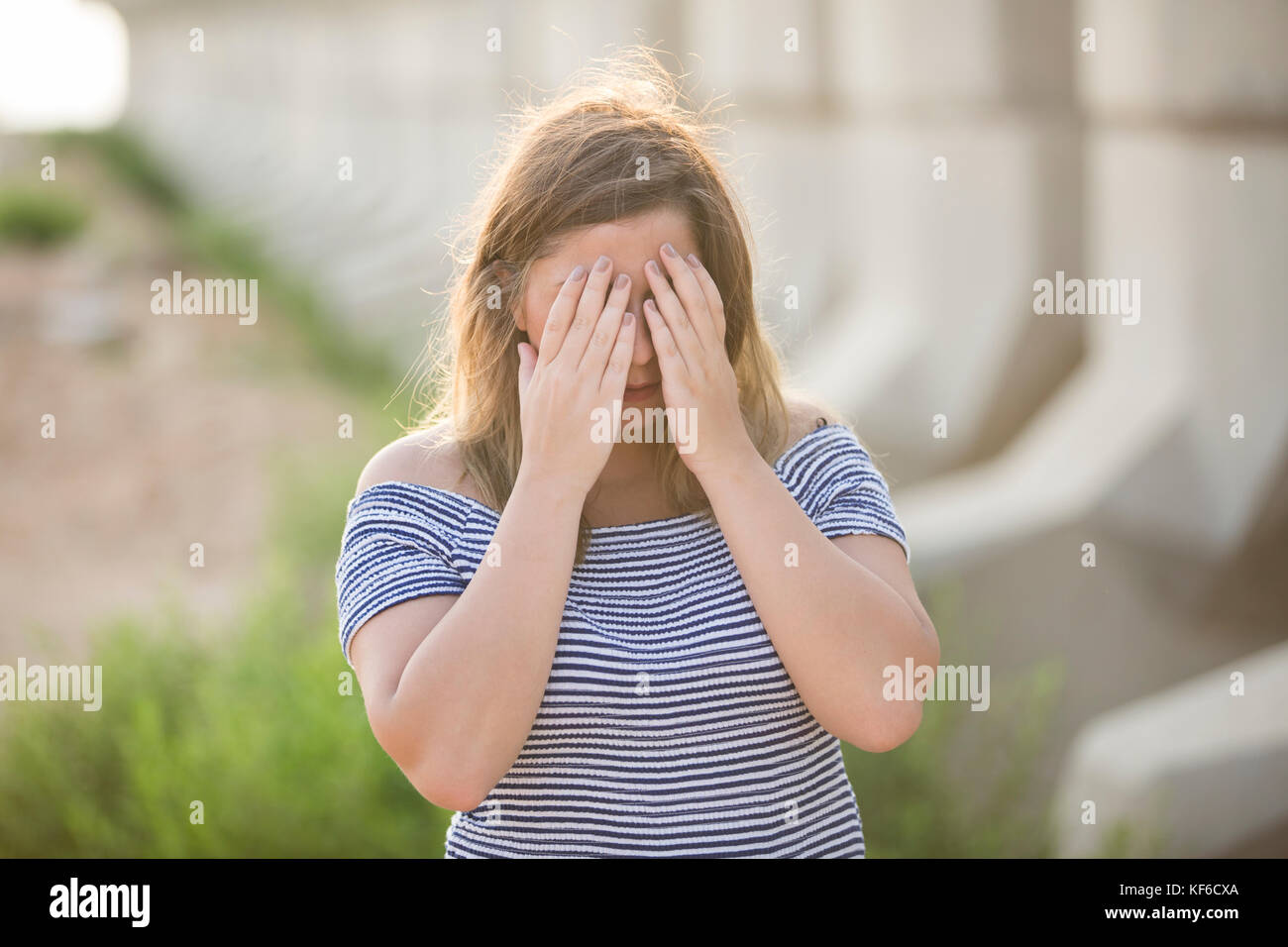 Stressed woman hiding face with hands outdoors Stock Photo - Alamy
