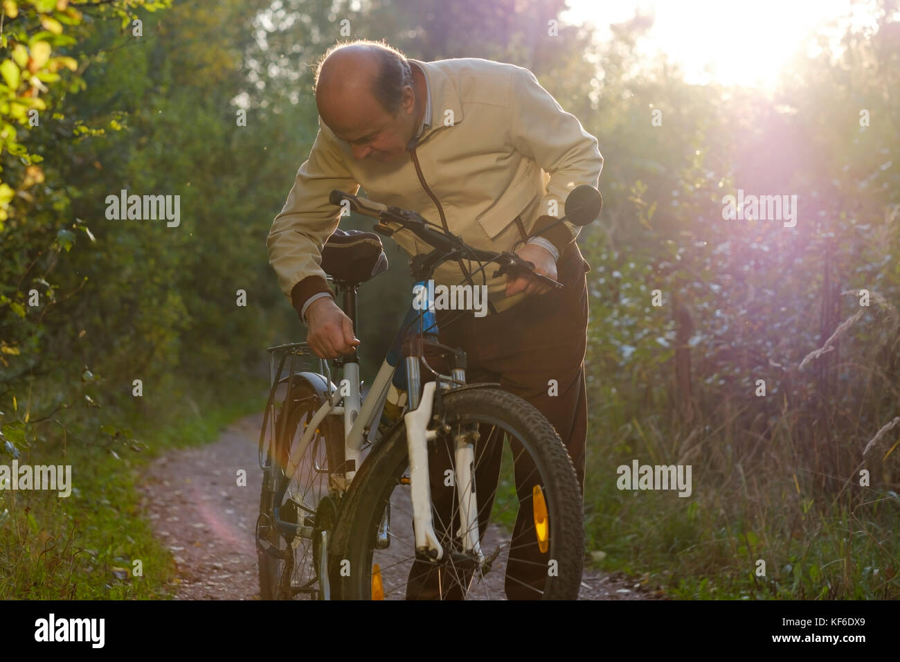 Senior caucasian man on cycle ride in countryside. Cycle is broken and ...