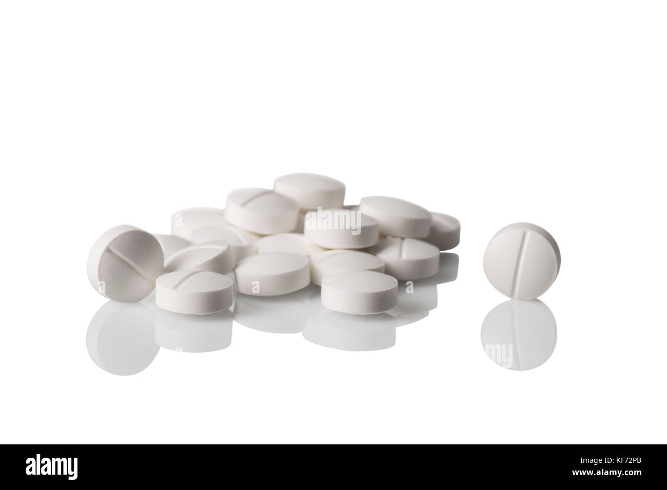 A small bunch of round, white pills on a counter with a reflection ...