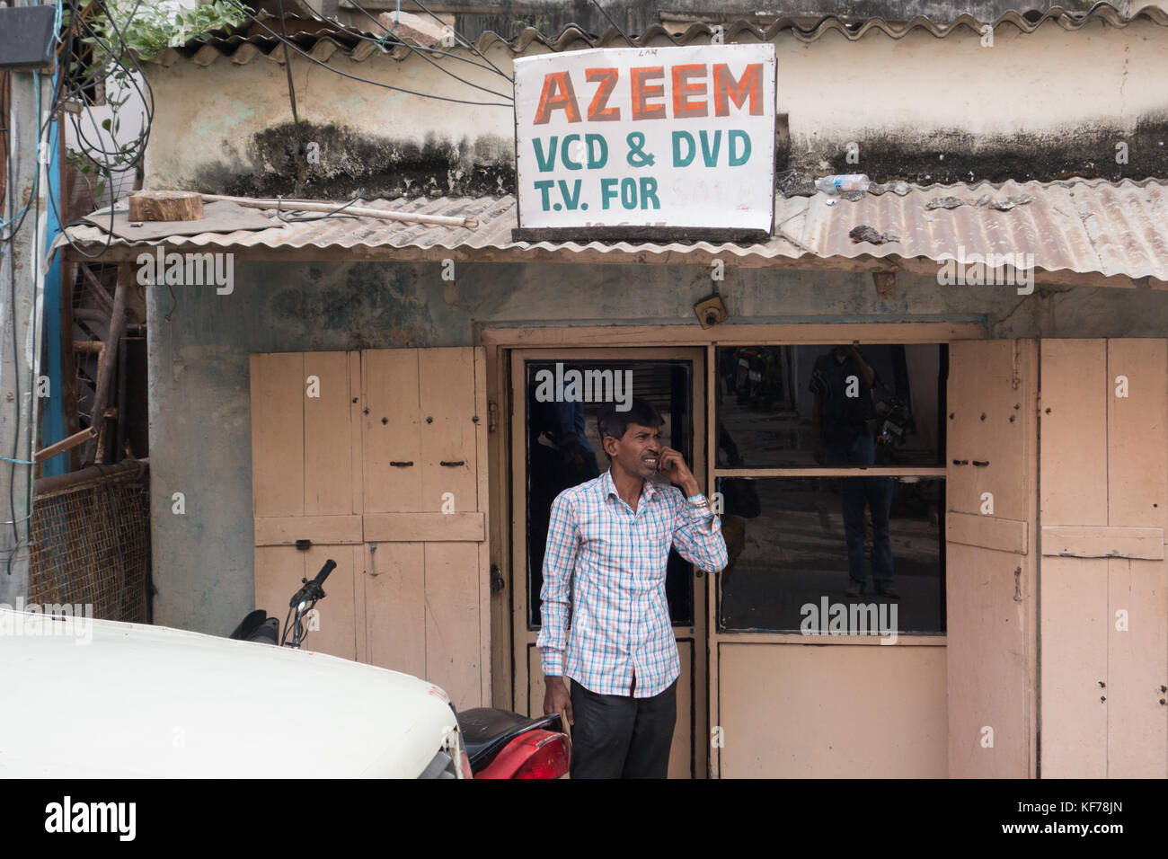 HYDERABAD, INDIA - OCTOBER 22,2017 A man stands in front of a DVD,VCD ...