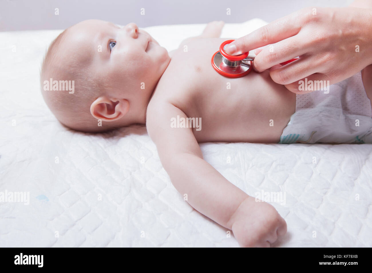 Pediatrician examines newborn baby boy with stethoscope. Baby is ...