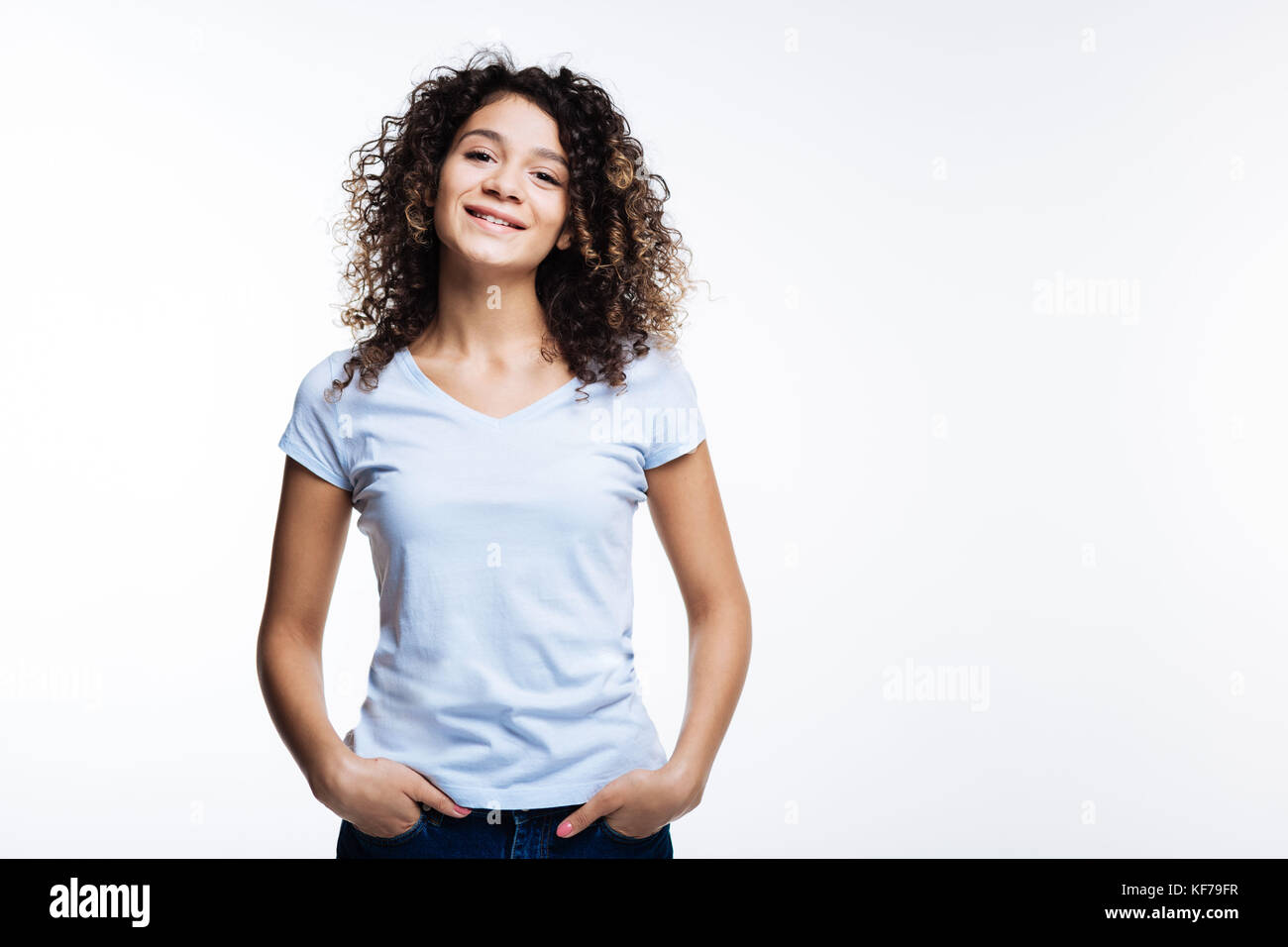 Cute curly woman holding hands in pockets Stock Photo - Alamy