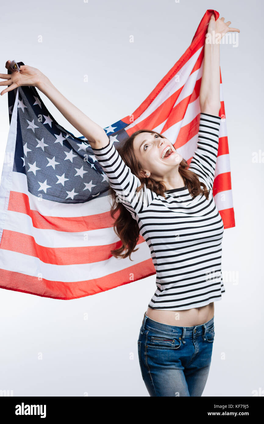 Slim cheerful woman lifting up US flag behind her back Stock Photo - Alamy