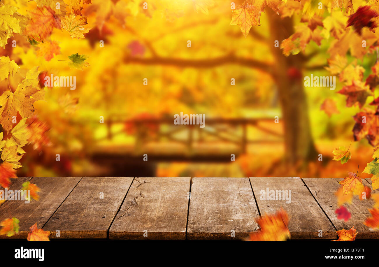 Autumn background with falling leaves and empty wooden table, ideal for ...