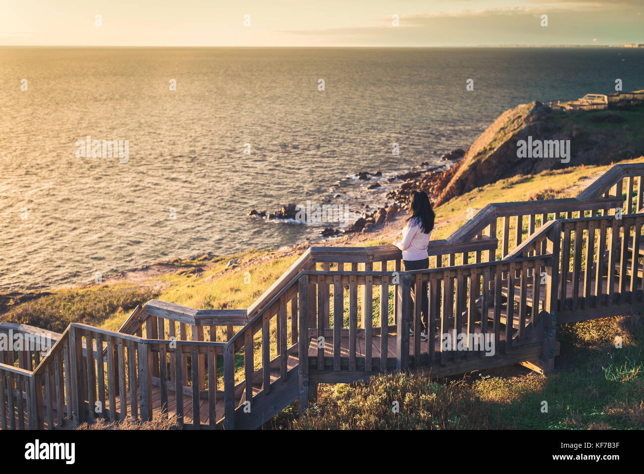 Woman walking down Hallett Cove boardwalk to enjoy sunset from beach ...