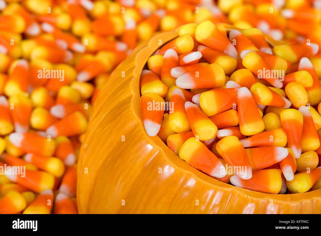 Ceramic decorative pumpkin filled with Halloween candy corn. Closeup ...