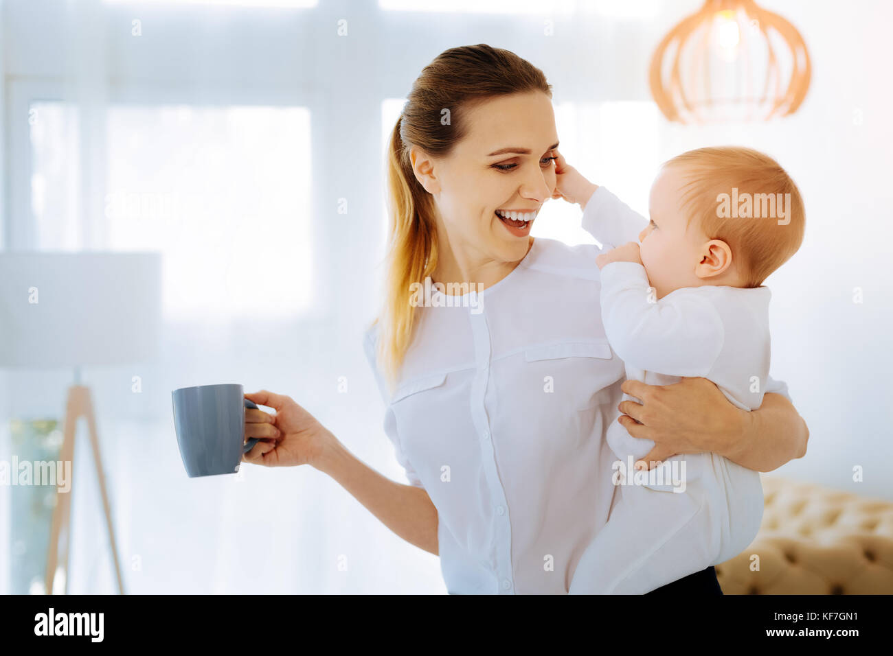 Positive mother drinking tea with her child Stock Photo - Alamy