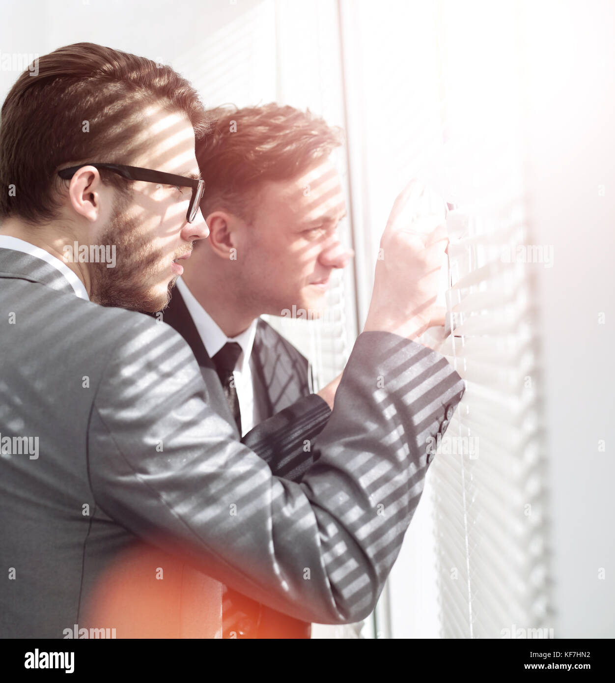 photo side view: a business team of three people looking out the office ...