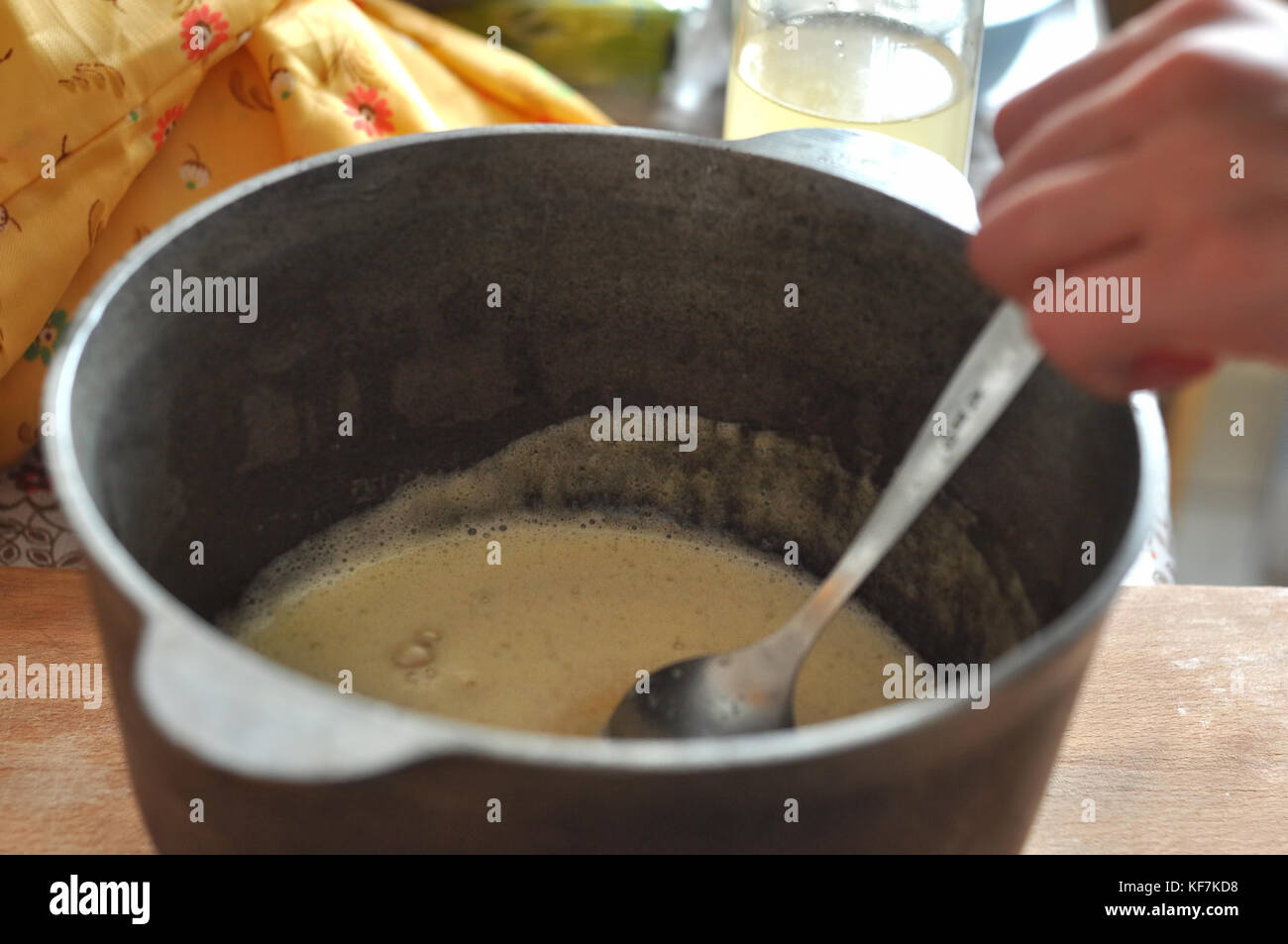 Female hand is mixing batter with a spoon in cast-iron bowl, close-up ...