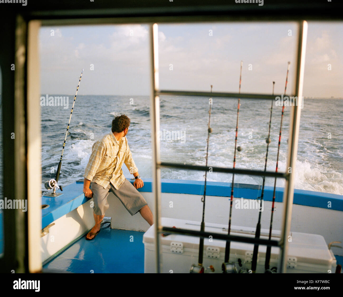 USA, Florida, man sitting on fishing boat heading out to sea, Destin ...
