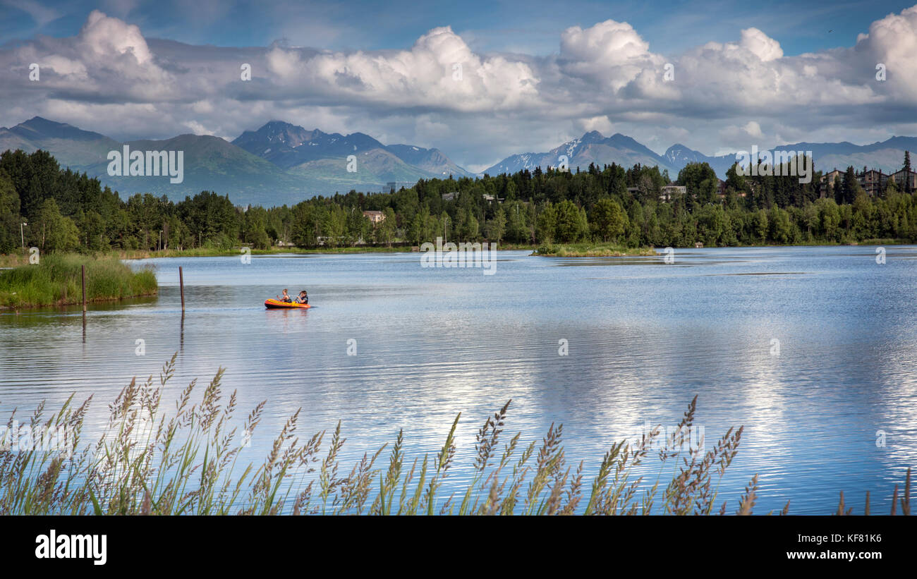 USA, Alaska, Anchorage, two individuals float in a raft in the lake ...