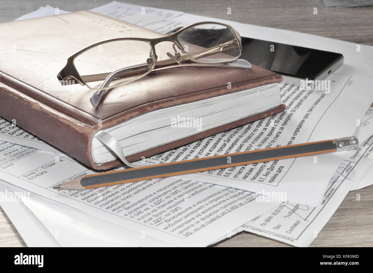 Business notebook with glasses, phone and pencil over documents Stock ...