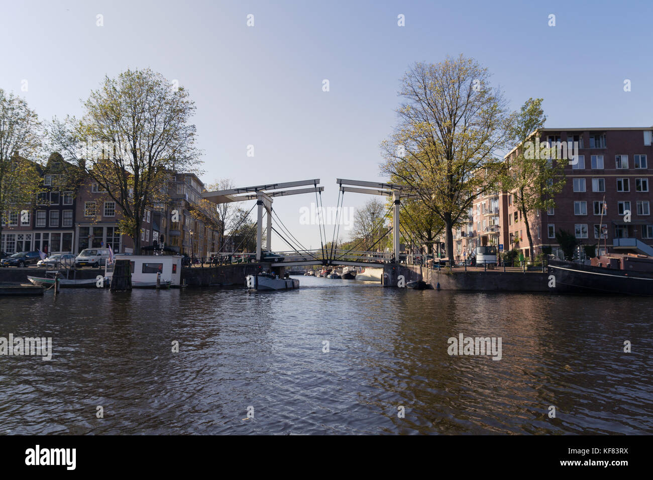 Small boat passing under a bridge on an Amsterdam canal on a sunny ...
