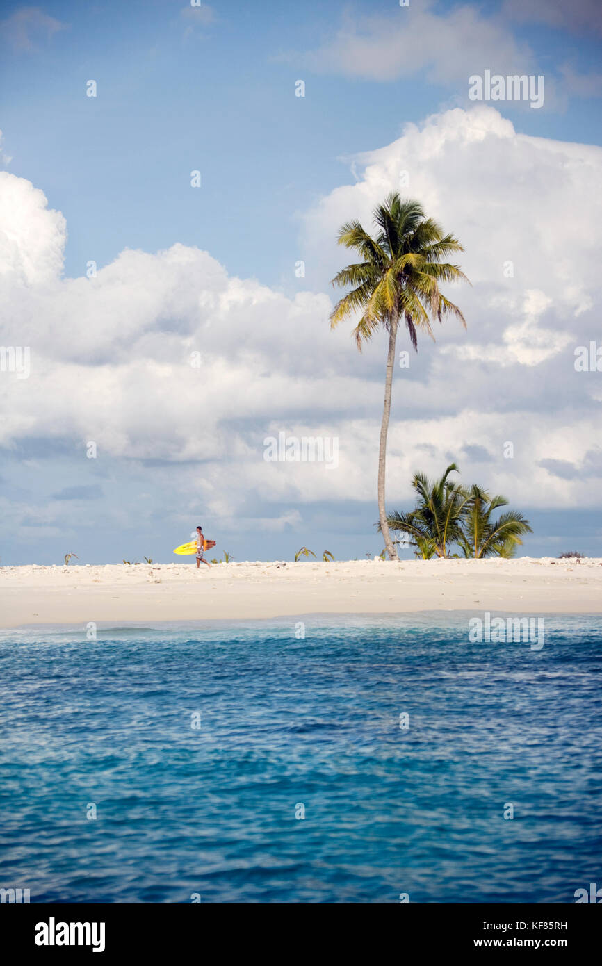 INDONESIA, Mentawai Islands, Kandui Resort, man walking with surfboard ...