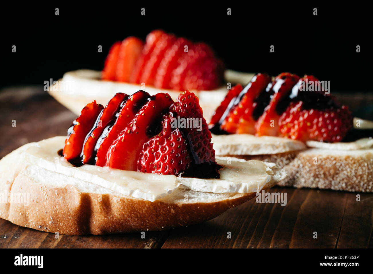 Canapes with brie cheese, fresh strawberries on rustic wooden surface ...