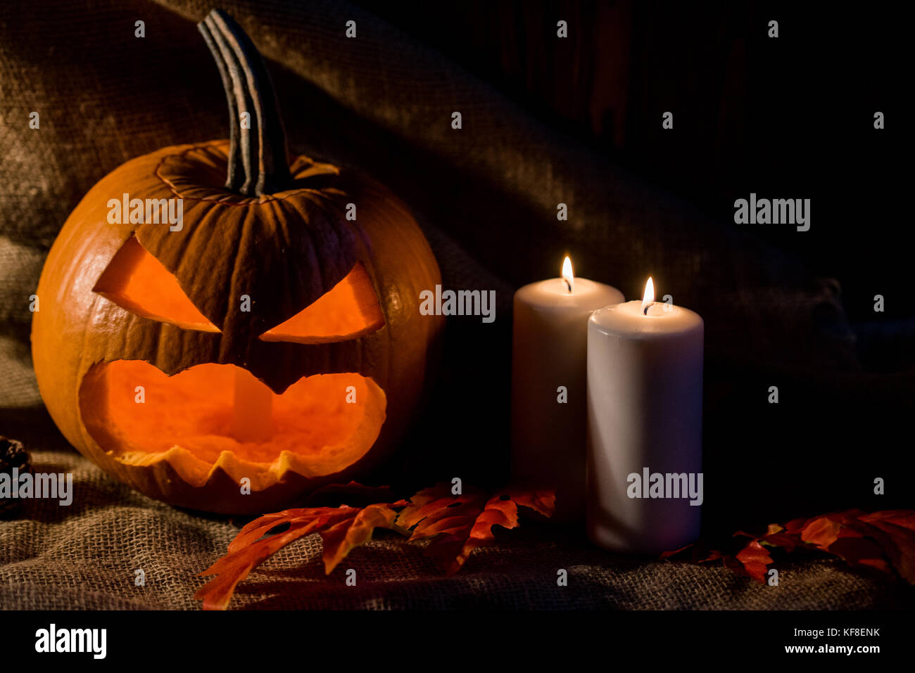 Scary jack-o-lantern, red leaves and candles Stock Photo - Alamy